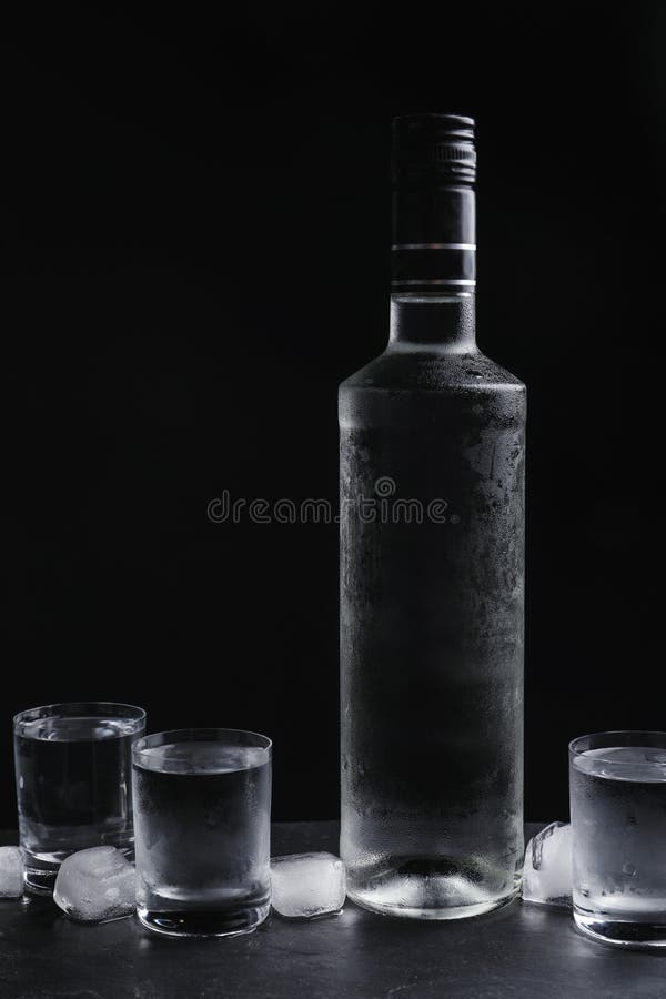 Bottle of Vodka and Shot Glasses with Ice on Table Against Black Background Stock Photo - Image ...