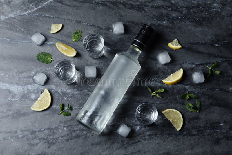 Bottle of Vodka, Shot Glasses, Lemon, Mint and Ice on Black Marble ...
