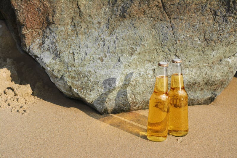 Bottles of Cold Beer Near Rock on Sandy Beach, Space for Text Stock ...