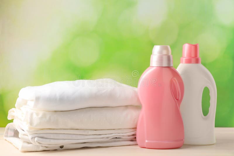 Bottles of Laundry Detergents and Clean Clothes on White Wooden Table ...