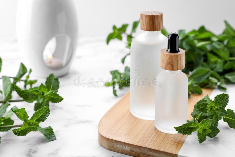 Bottles of Mint Essential Oil and Fresh Leaves on White Marble Table ...