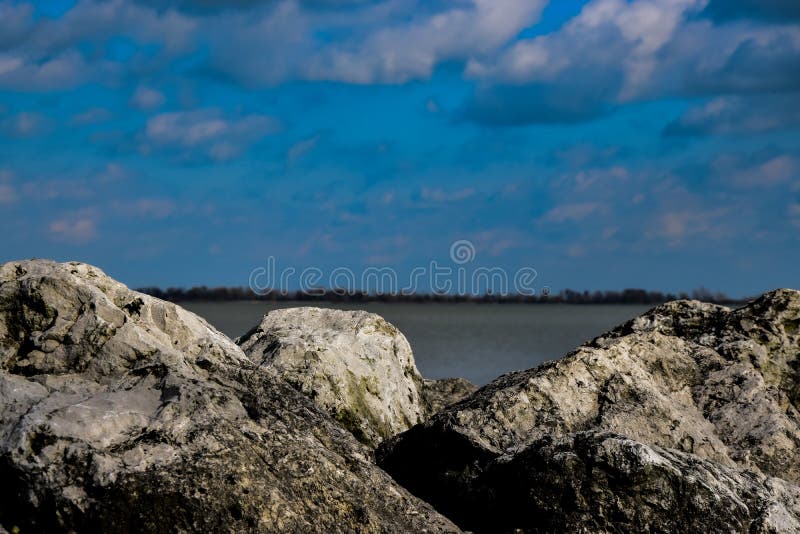 Boulders on the shoreline stock photo. Image of horizon - 231487718