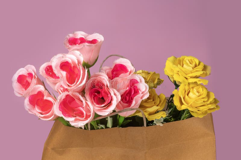 Bouquet of Artificial Pink and Yellow Roses in a Paper Bag on a Pink ...