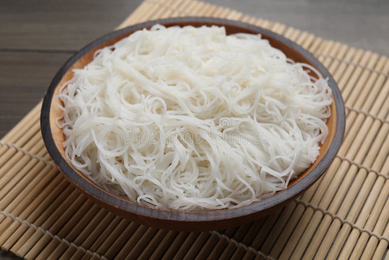 Bowl with Cooked Rice Noodles and Straw Mat on Table, Closeup Stock ...