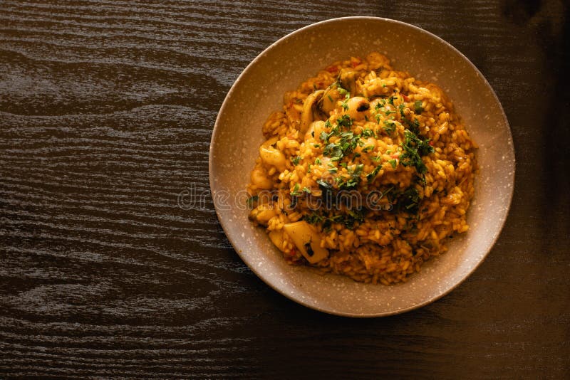 Bowl of Delicious Rice with Cuttlefish and Prawns on a Wooden Table ...