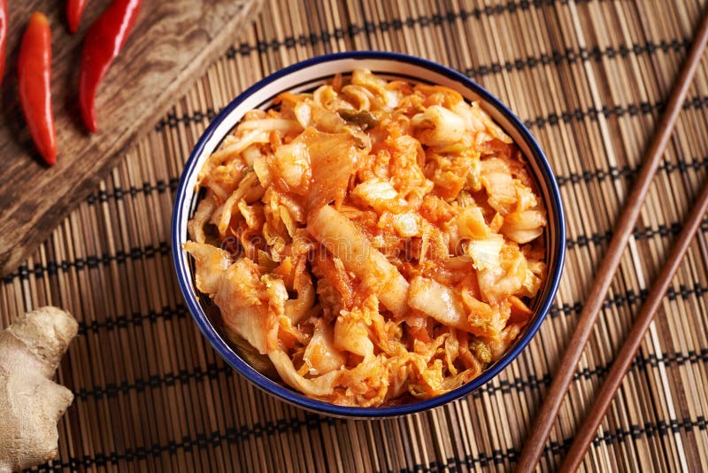 A Bowl of Fermented Kim Chi on a Table with Chilli Peppers, Ginger and ...