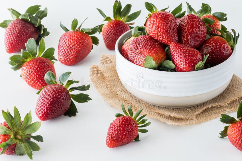 A Bowl Full of Juicy Ripe Strawberries with Several Scattered Around on ...