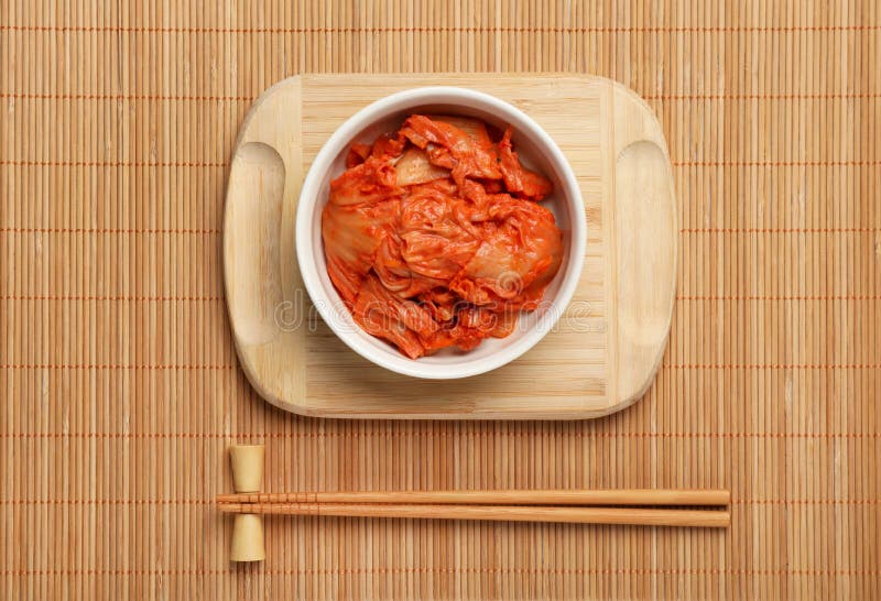 Bowl of Spicy Cabbage Kimchi and Chopsticks on Bamboo Mat, Flat Lay ...
