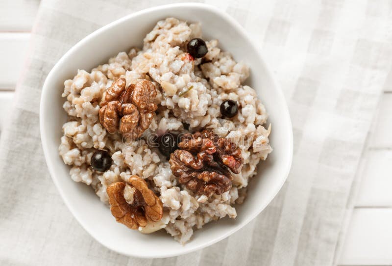 Bowl with Tasty Oatmeal, Berries and Nuts on White Table Stock Image ...