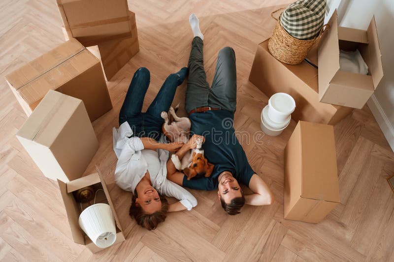 Between Boxes, Lying Down. Young Couple with Dog are Moving To New Home ...