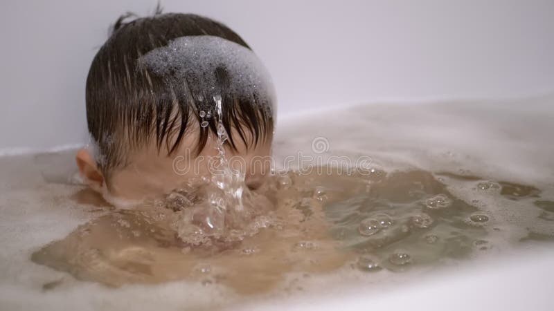 Boy Bathes in Water with Foam in Bathtub, Submerges Under Water, Blows ... Boy Bathes in Water with Foam in Bathtub, Submerges Under Water, Blows ...