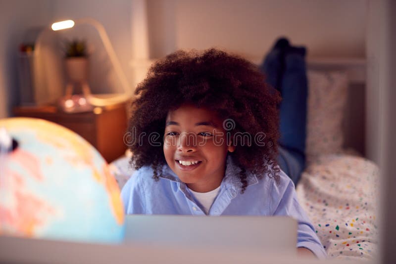 Boy in Bedroom at Night Lying on Bed Using with Laptop with Illuminated ...