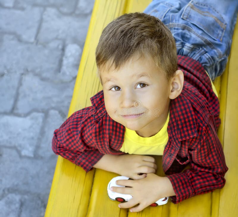 Boy on bench stock image. Image of holding, playful, lying - 75892895