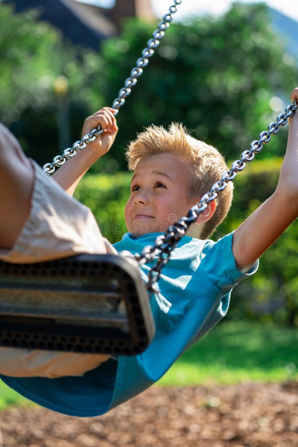 A Boy in a Blue T-shirt Rides on a Swing and Smiles Stock Photo - Image ...