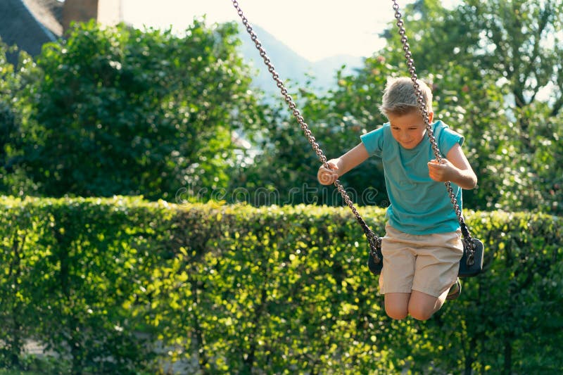 A Boy in a Blue T-shirt Rides on a Swing and Smiles Stock Image - Image ...