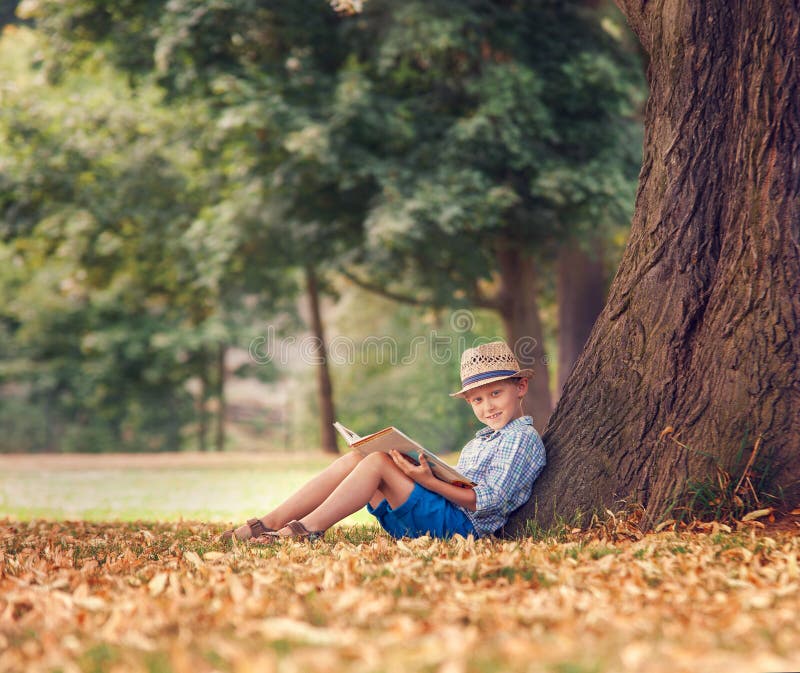 Boy with Book Sitting Under Tree in Park Stock Image - Image of ...