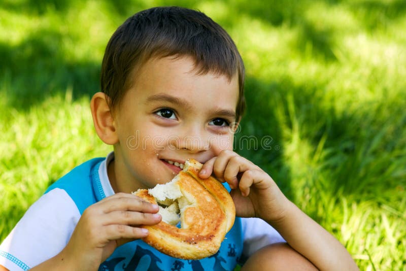 Little Boy Eating a Bun on Nature Stock Image - Image of hungry ...