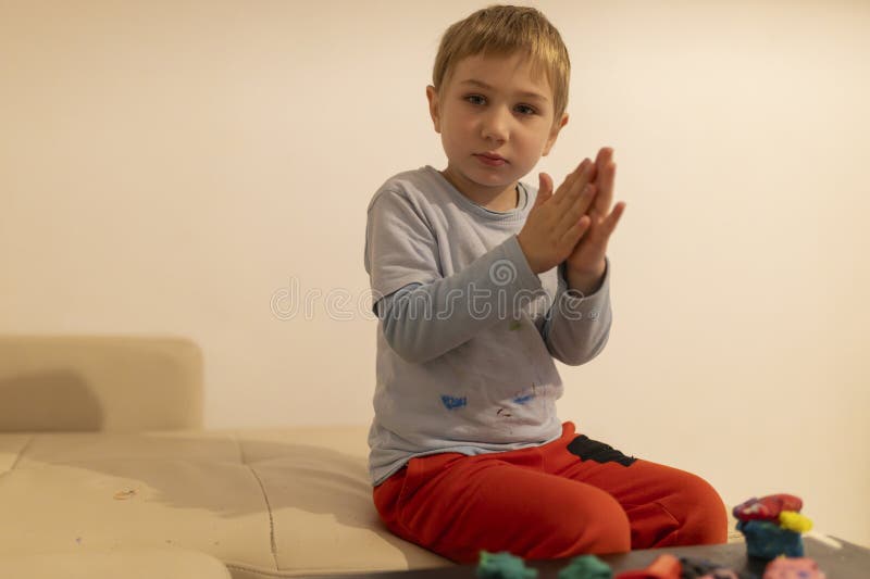 Boy Clapping Hands while Playing with Modeling Clay on Sofa Stock Photo ...