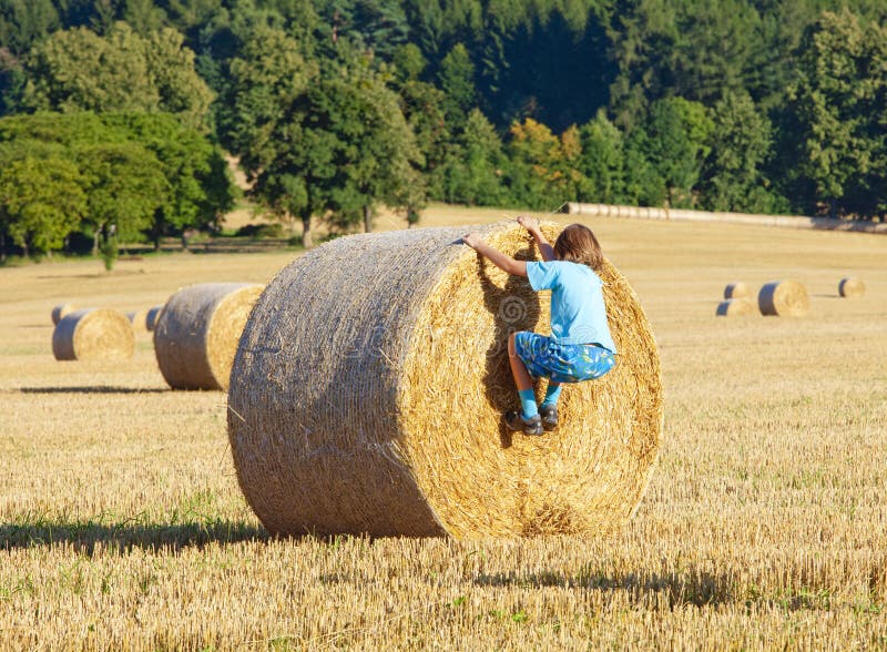 Boy Climbing a Bale of Hay on a Field Stock Photo - Image of summer ...
