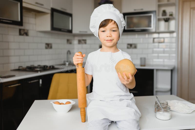 Boy in Cook Hat Sitting at a Kitchen Counter. Little Boy in Kitchen ...