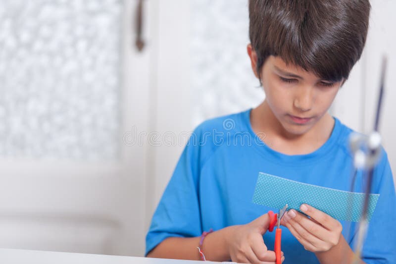 Boy Cuts Out Blue Patterned Paper with Red Scissors Stock Image - Image ...