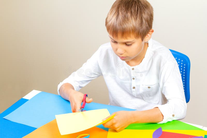 Boy Cutting Colored Paper with Scissors at the Table Stock Photo ...
