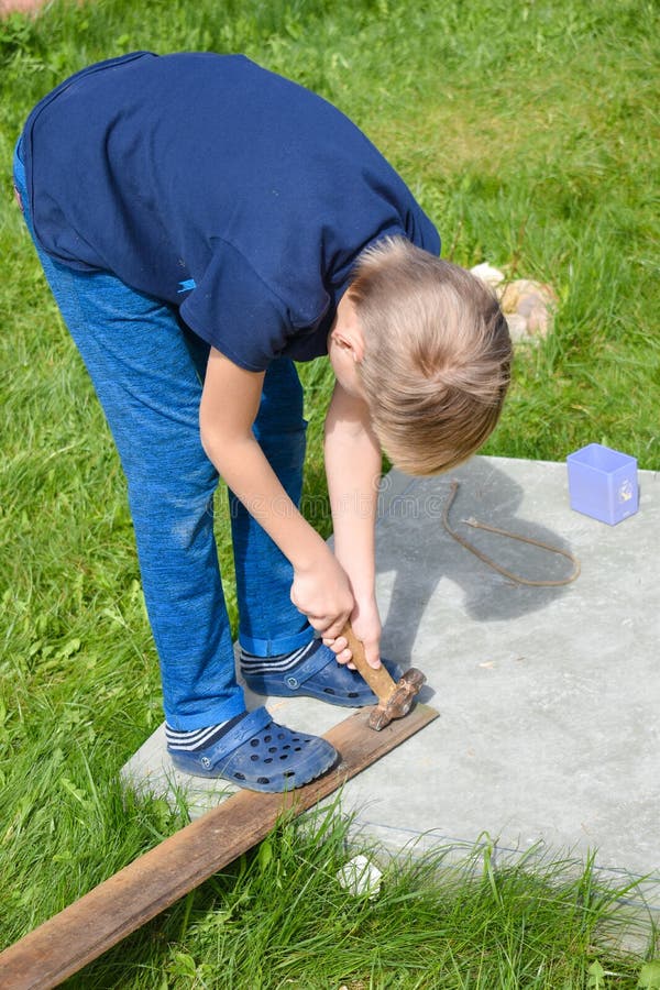 Boy Sawing Wood. a Boy Works in the Garden. Children`s Workshop Outside ...