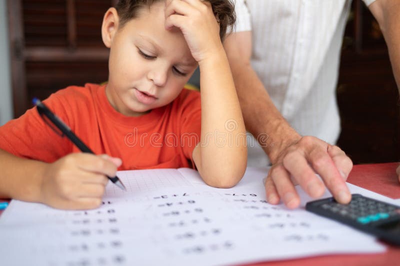A Boy Does His Math Homework while His Father Stands Next To Him ...