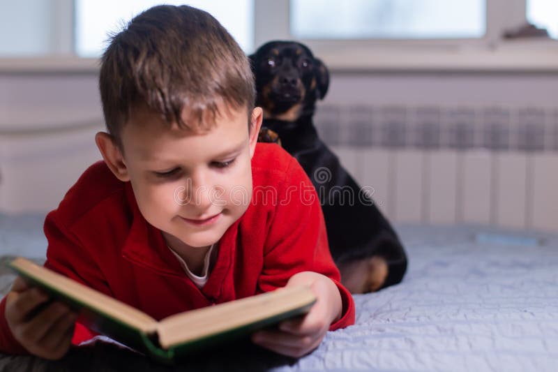 Boy with dog reads a book stock image. Image of blond - 201110633