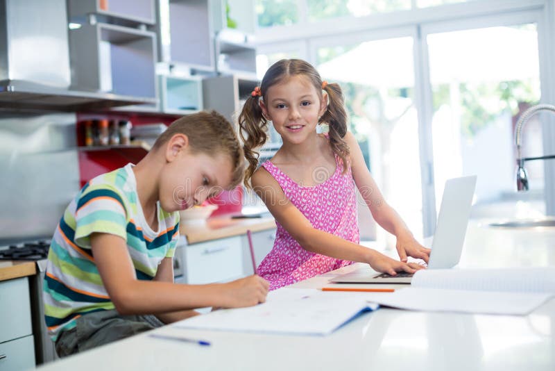 Boy Doing His Homework while Girl Using Laptop in Kitchen Stock Image ...