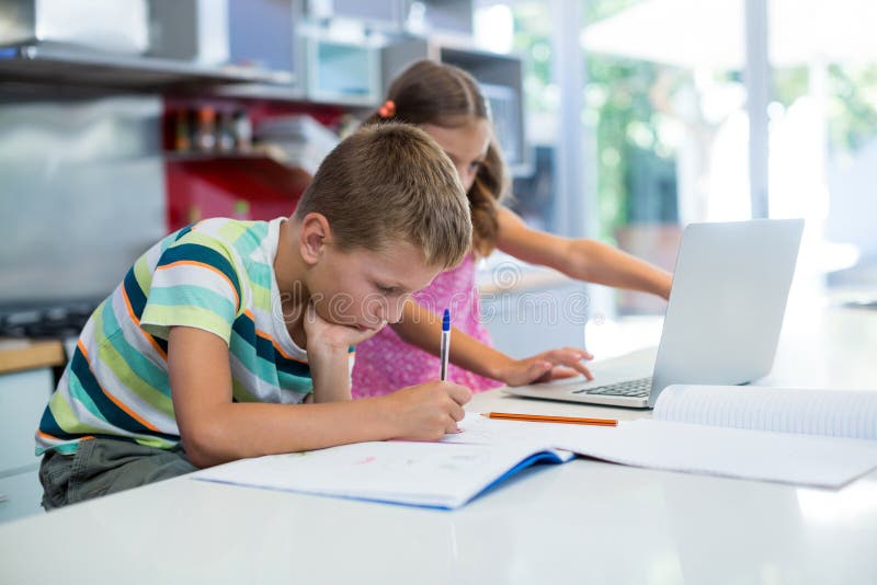 Boy Doing His Homework while Girl Using Laptop in Kitchen Stock Image ...