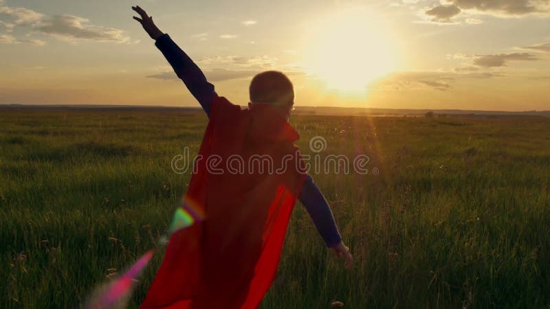 Video: Boy dressed with a Superman cape running in a field, looking ...