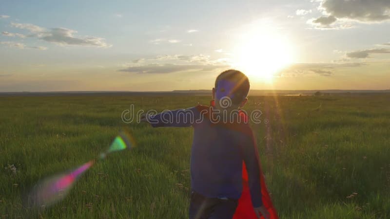 Boy Dressed with a Superman Cape Running in a Field, Looking into the ...