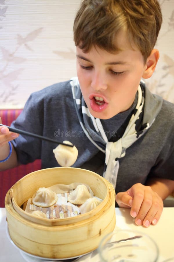 Boy Eating Chinese Dumplings from a Wooden Stock Photo - Image of ...
