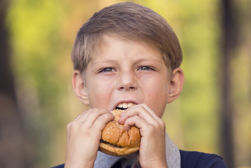 Boy eating a hamburger stock image. Image of bread, green - 44702007