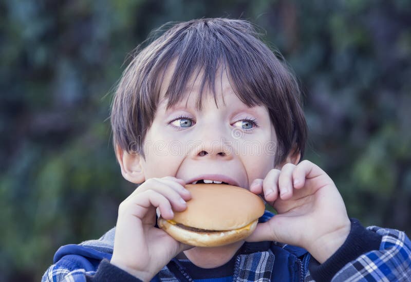 Boy eating a hamburger stock image. Image of enjoy, green - 45266639