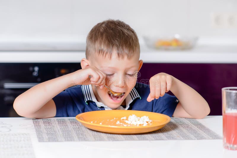 Boy Eating Last Bite of Food at Kitchen Table Stock Photo - Image of ...