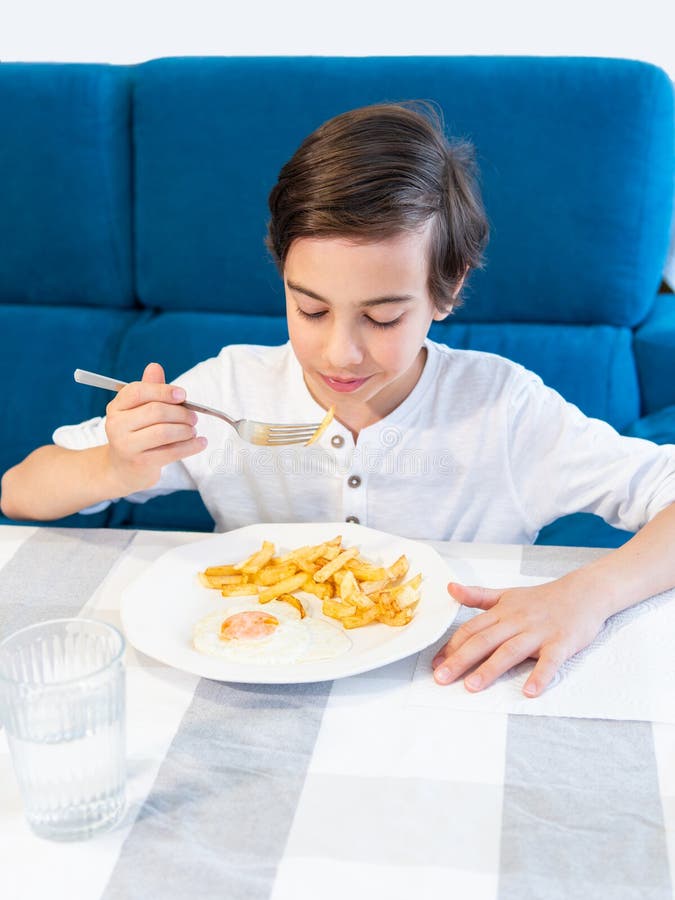 Boy eating meal at table stock photo. Image of table - 331393148