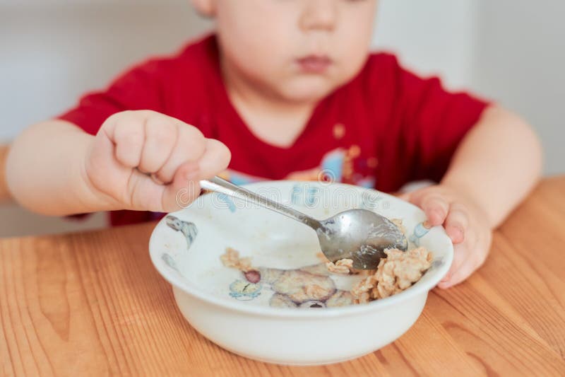 A Young Child is Eating Breakfast at the Kitchen Table Stock Photo ...
