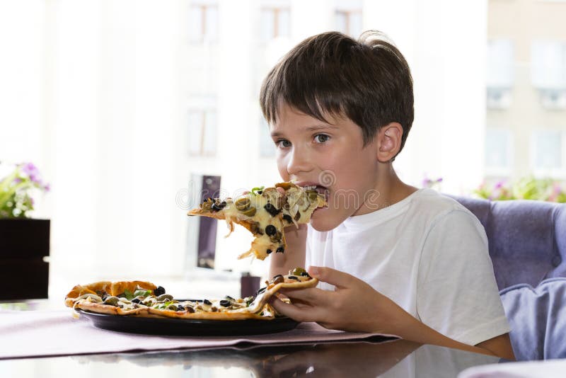 The boy is eating pizza stock photo. Image of portion - 97603864