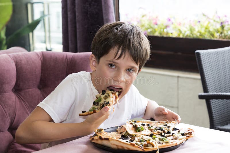 The boy is eating pizza stock photo. Image of cute, eyes - 97604396