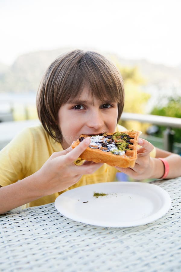 A Boy is Eating Waffles in a Street Cafe Stock Image - Image of ...