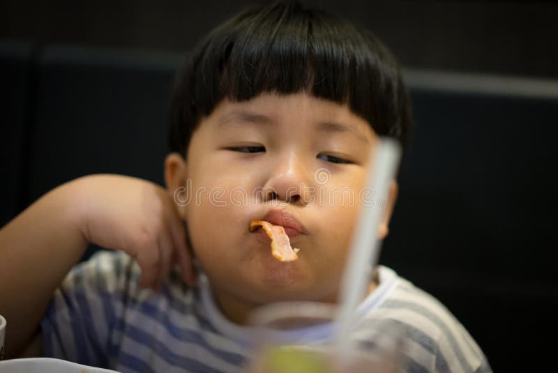 A boy eats bacon. stock image. Image of face, holding - 105886203