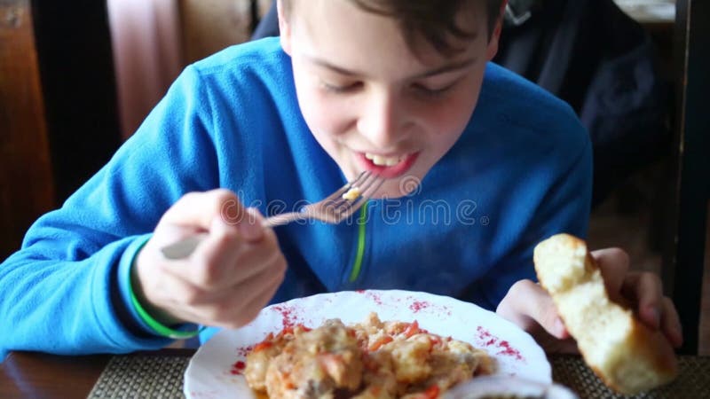 Boy Eats Meat with Vegetables Sitting at Table in Stock Footage - Video ...