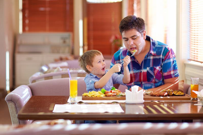 Boy Feeding Father in Restaurant Stock Photo - Image of cafe, happy ...