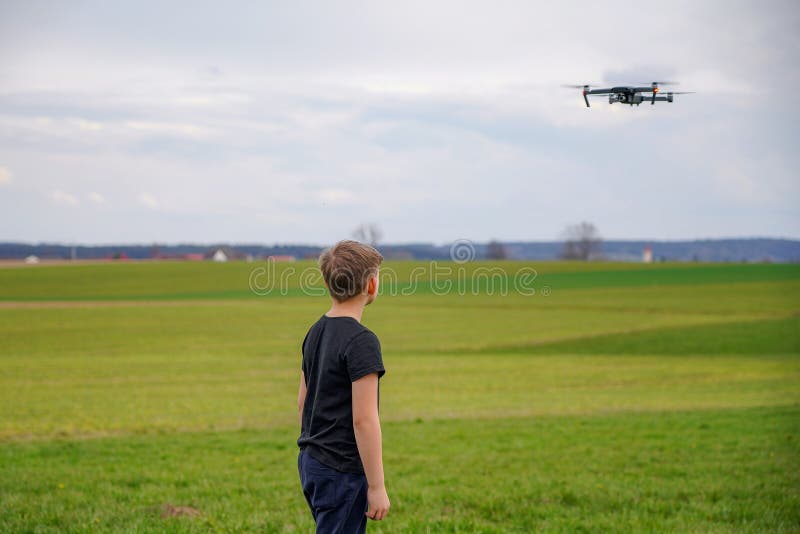 A Boy in a Field Launches a Quadcopter and Controls it from the Remote ...
