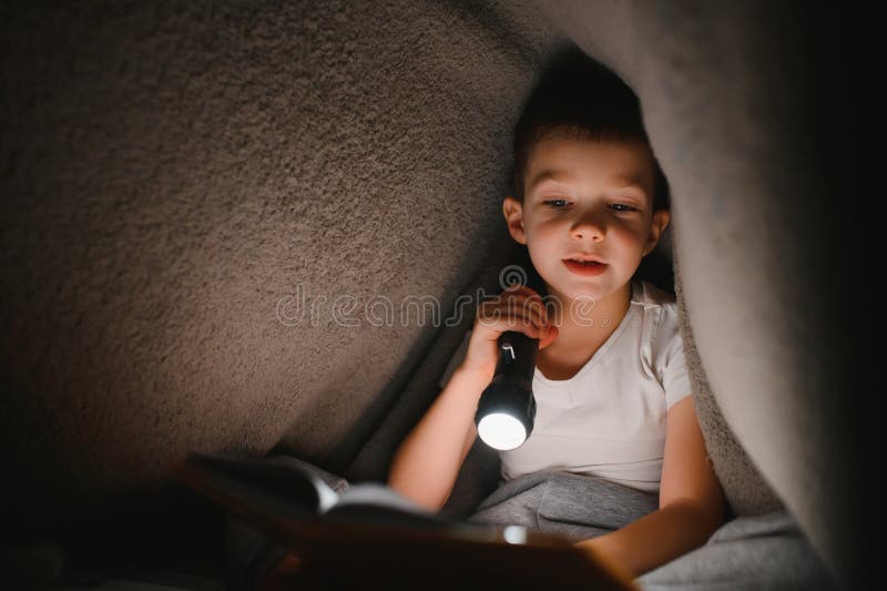 Boy with Flashlight Reading Book Under Blanket at Home Stock Image ...
