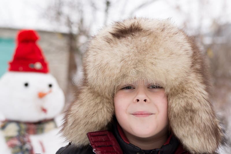 The Boy in a Fur Hat Around Snowman Stock Photo - Image of clothing ...