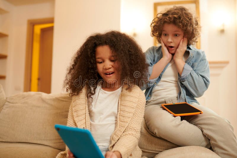 A Boy and a Girl with Devices Watching Something Online Stock Photo ...