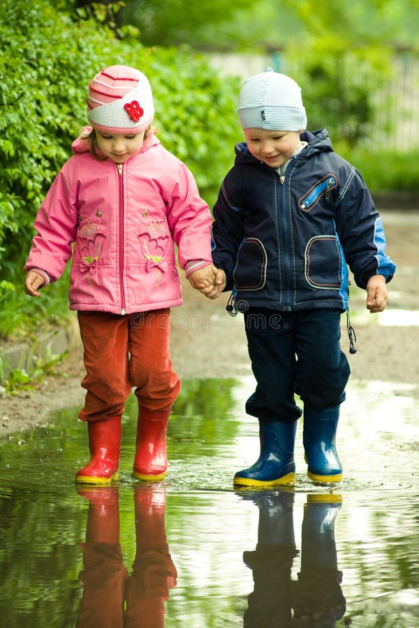 Boy and girl in the puddle stock photo. Image of outdoor - 12867848